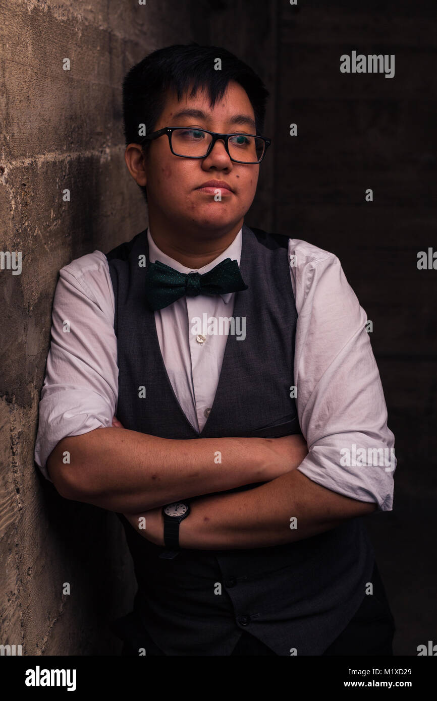 Young transgender man in formal clothing poses in a grungy urban ...
