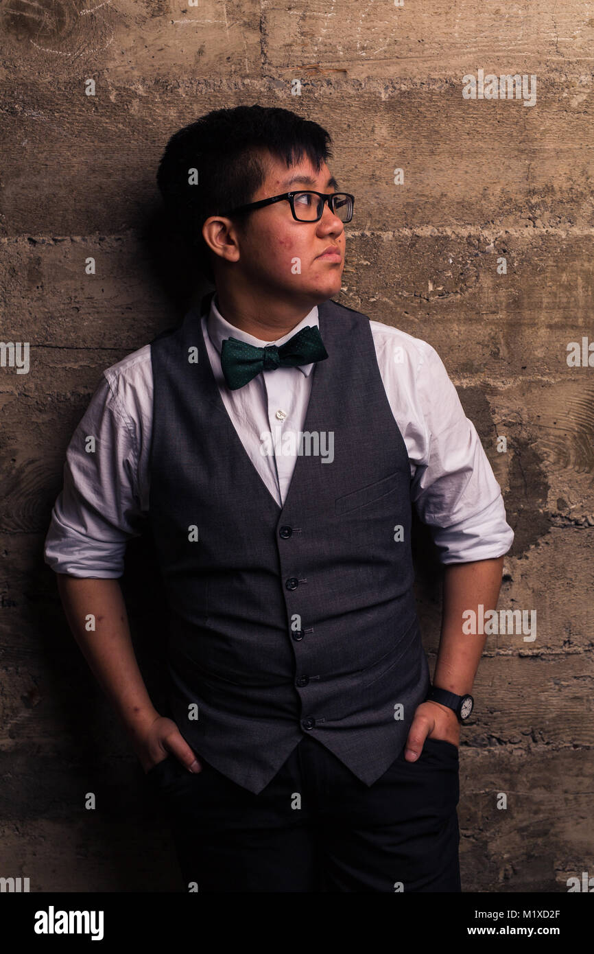 Young transgender man in formal clothing poses in a grungy urban ...