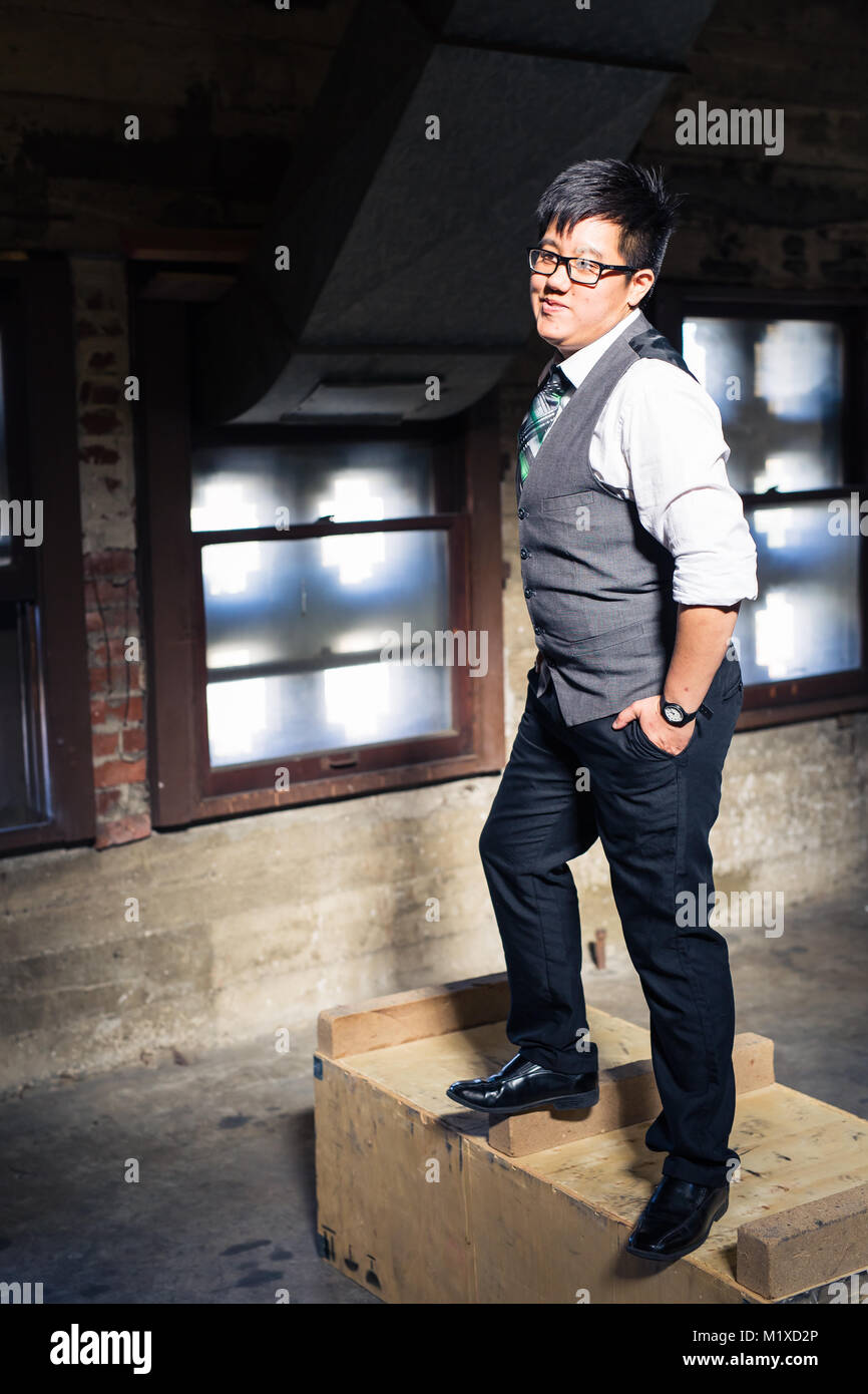 Young transgender man in formal clothing poses in a grungy urban ...