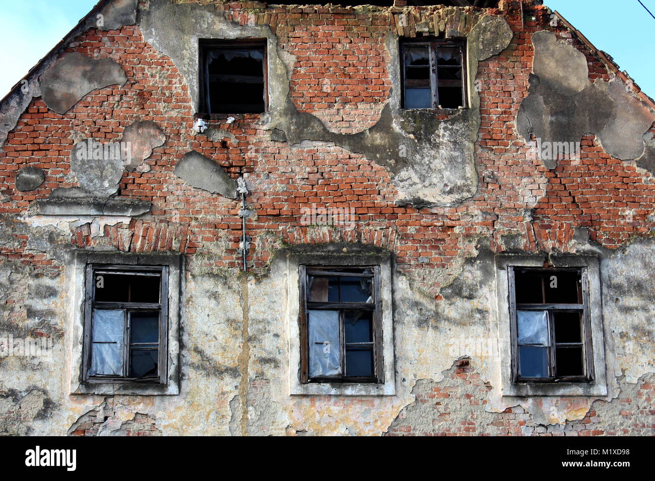 Abandoned old ruined house closeup of broken walls with missing bricks, broken windows and ...