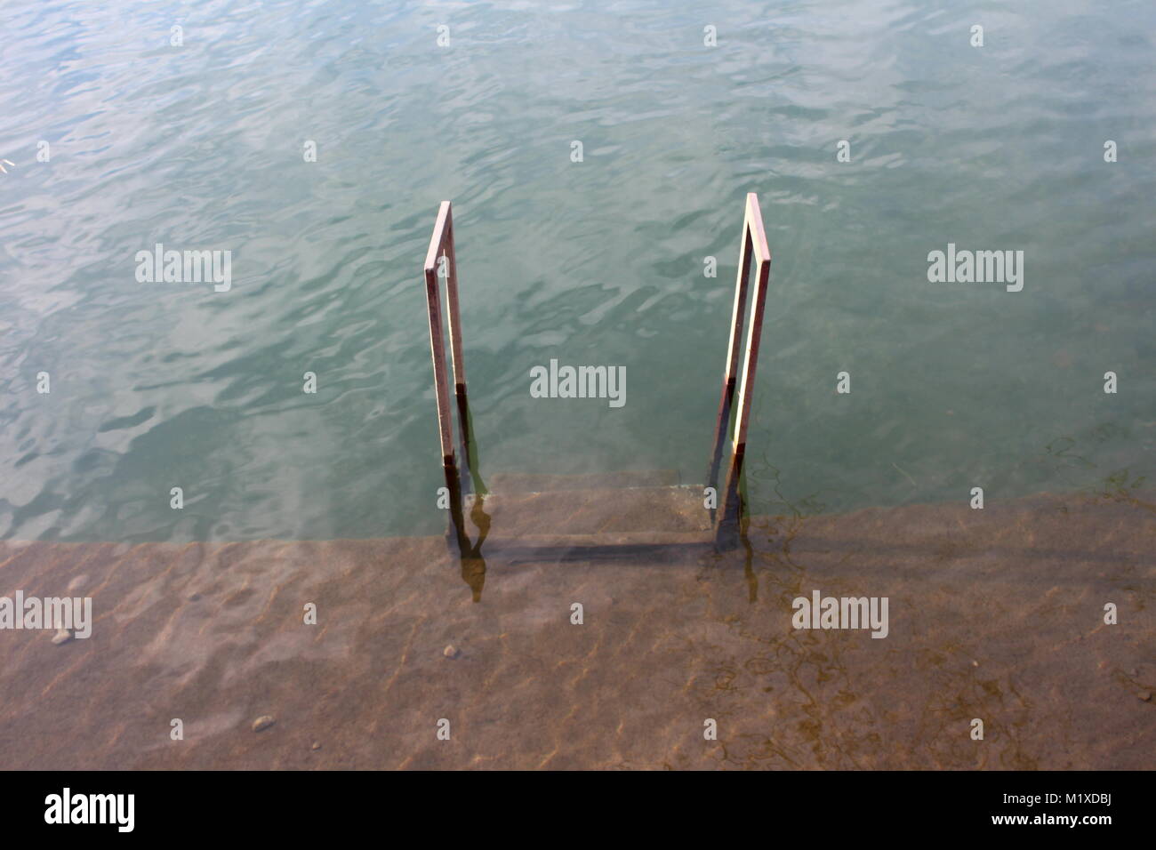 Flooded metal steps covered in mud with rectangle pipe handrail ...