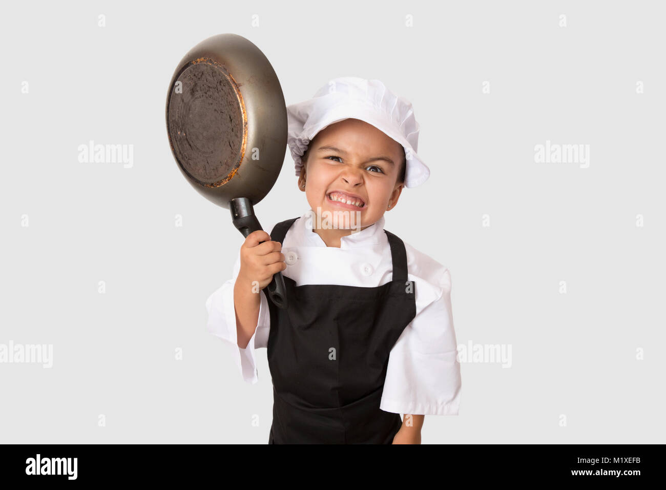 Portrait of a funny four years girl cooking in the kitchen with angry ...