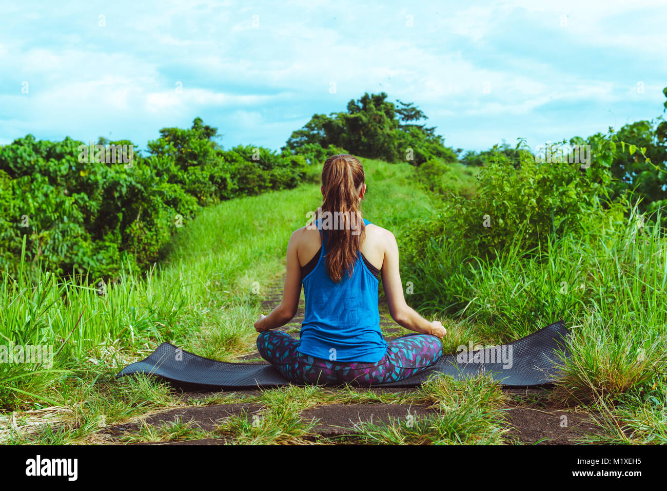 Lotus pose on green nature background. Back view Stock Photo - Alamy