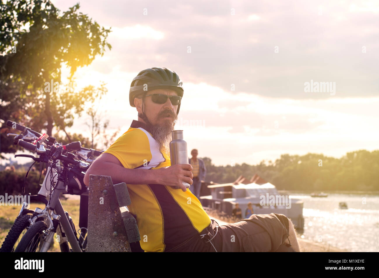 Male cyclist resting on a park bench after doing some training on his ...