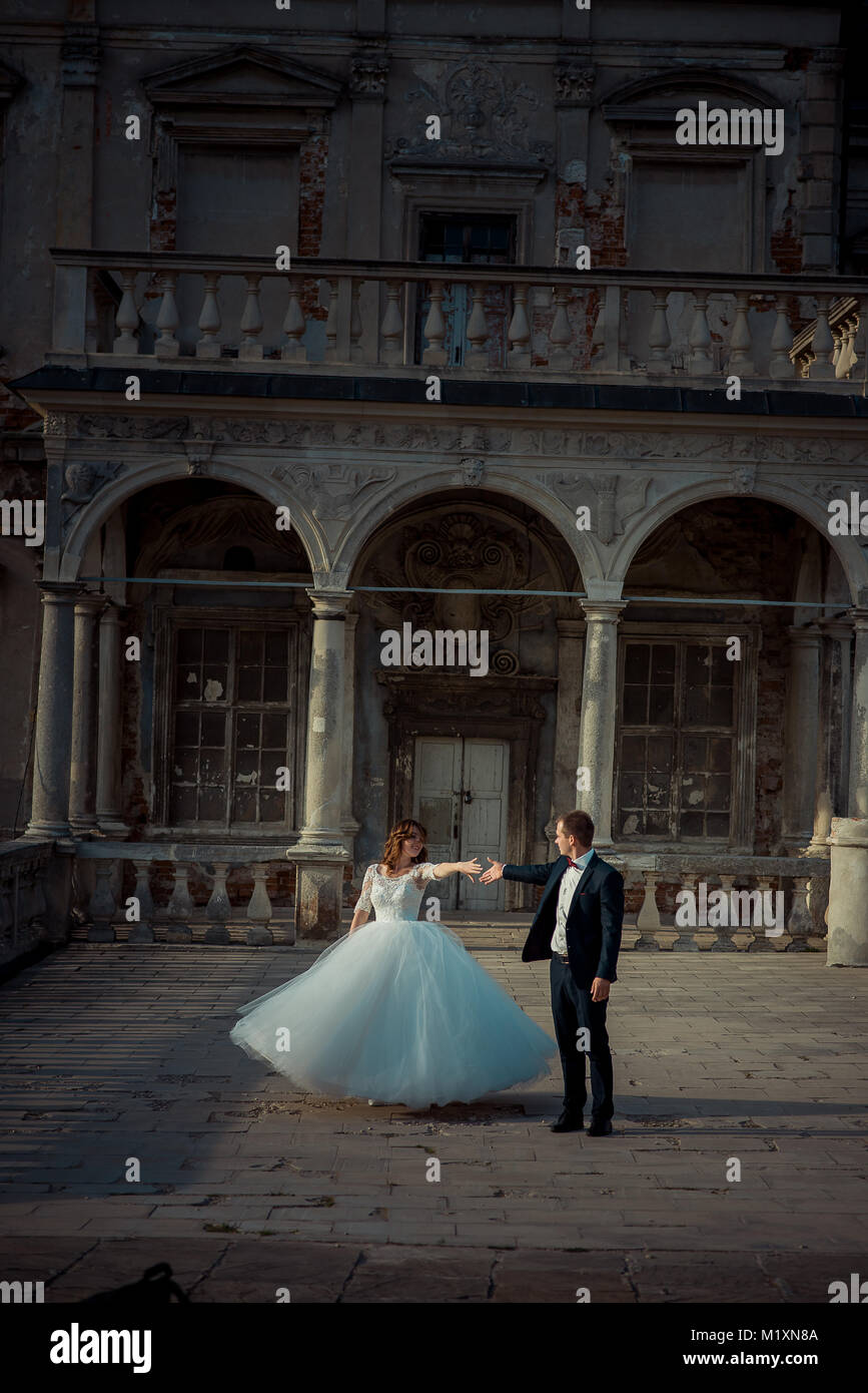 Dancing newlyweds on the balcony of the old outdoor castle. Full-length ...