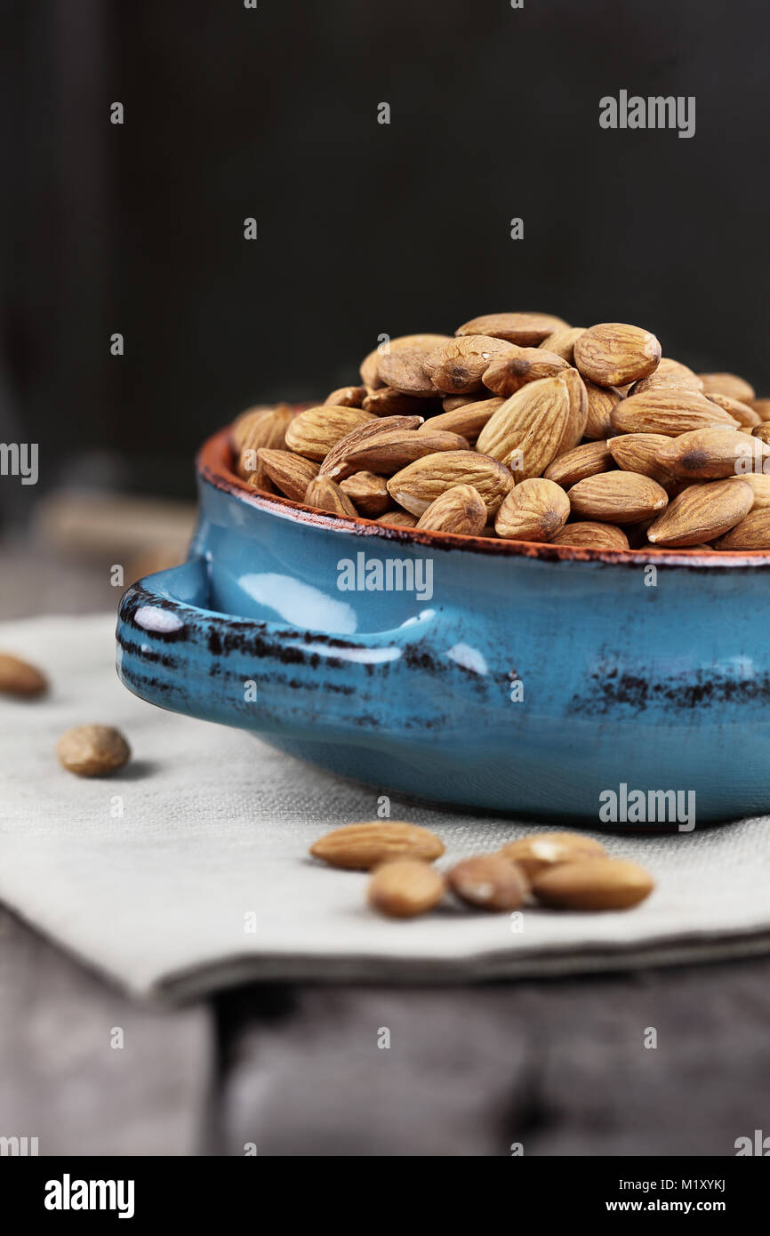 Whole almonds in bowl over a wooden table against a rustic background ...