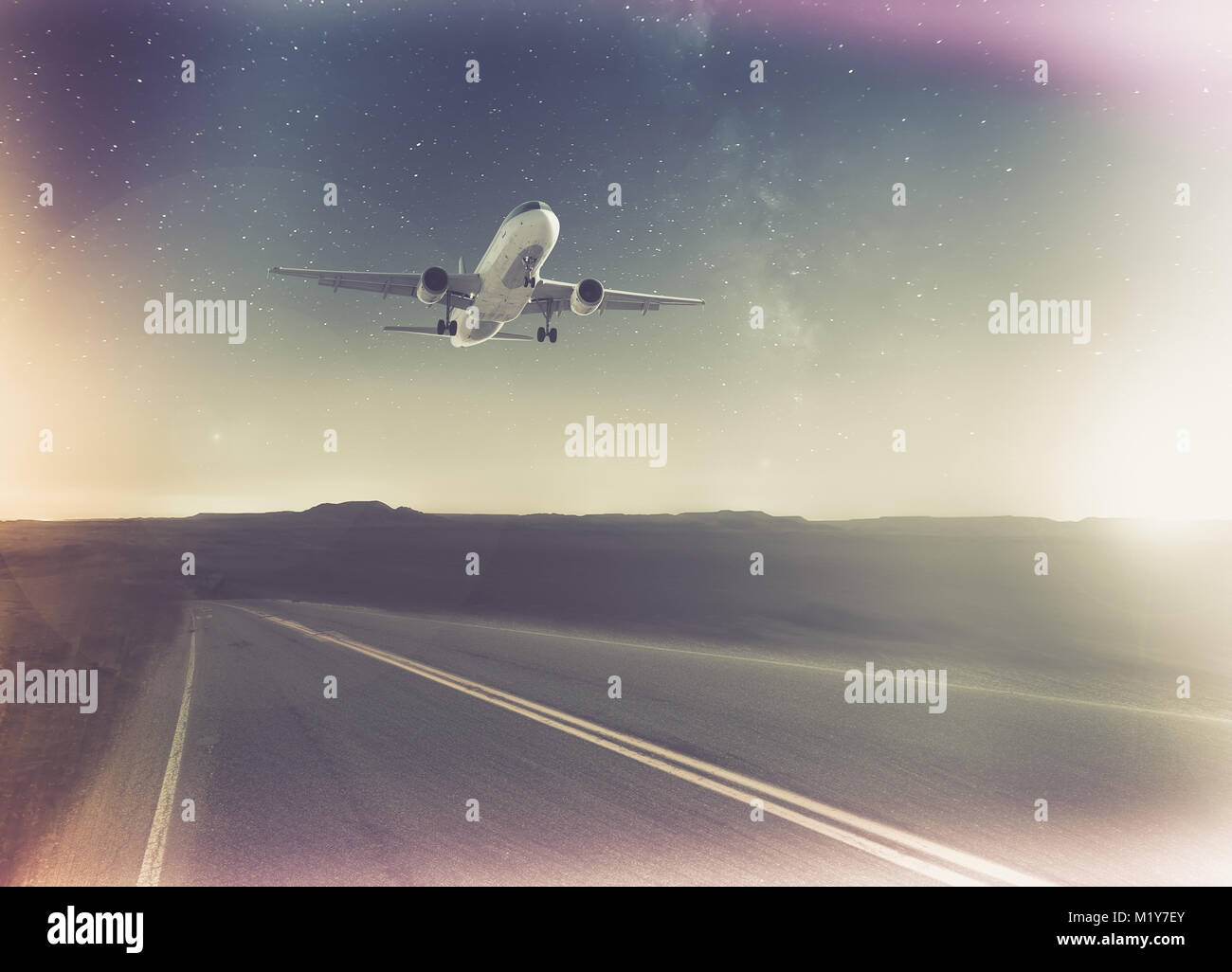 Airplane soaring high in night sky against plain background and road ...