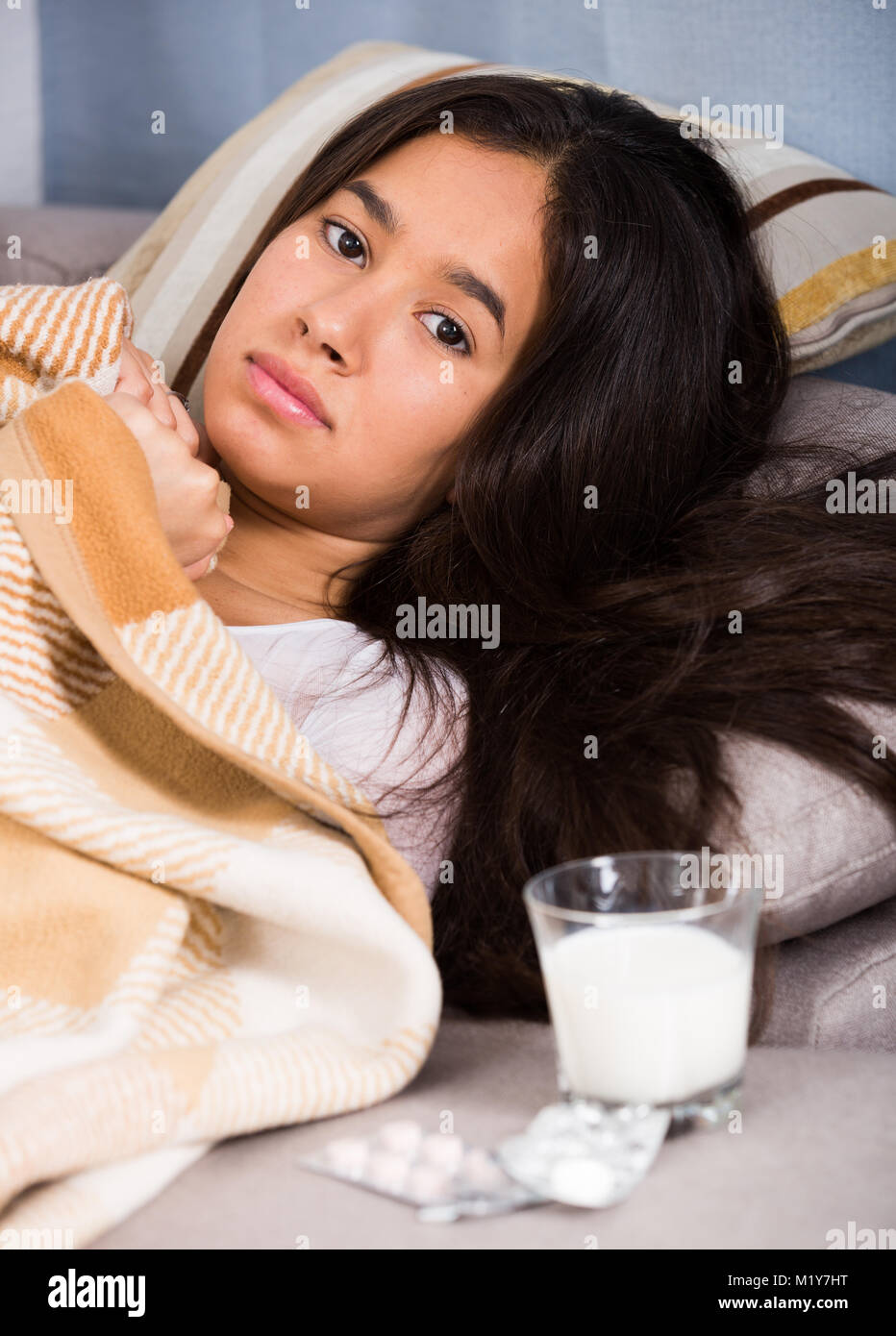 Sick girl at home lying at sofa near pills and glass of milk Stock ...