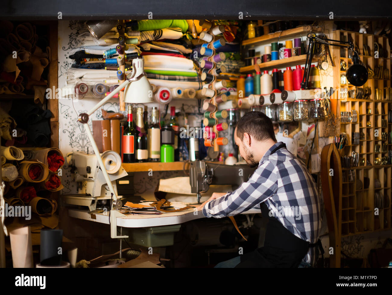 positive european male worker sewing stitches on belt in leather ...