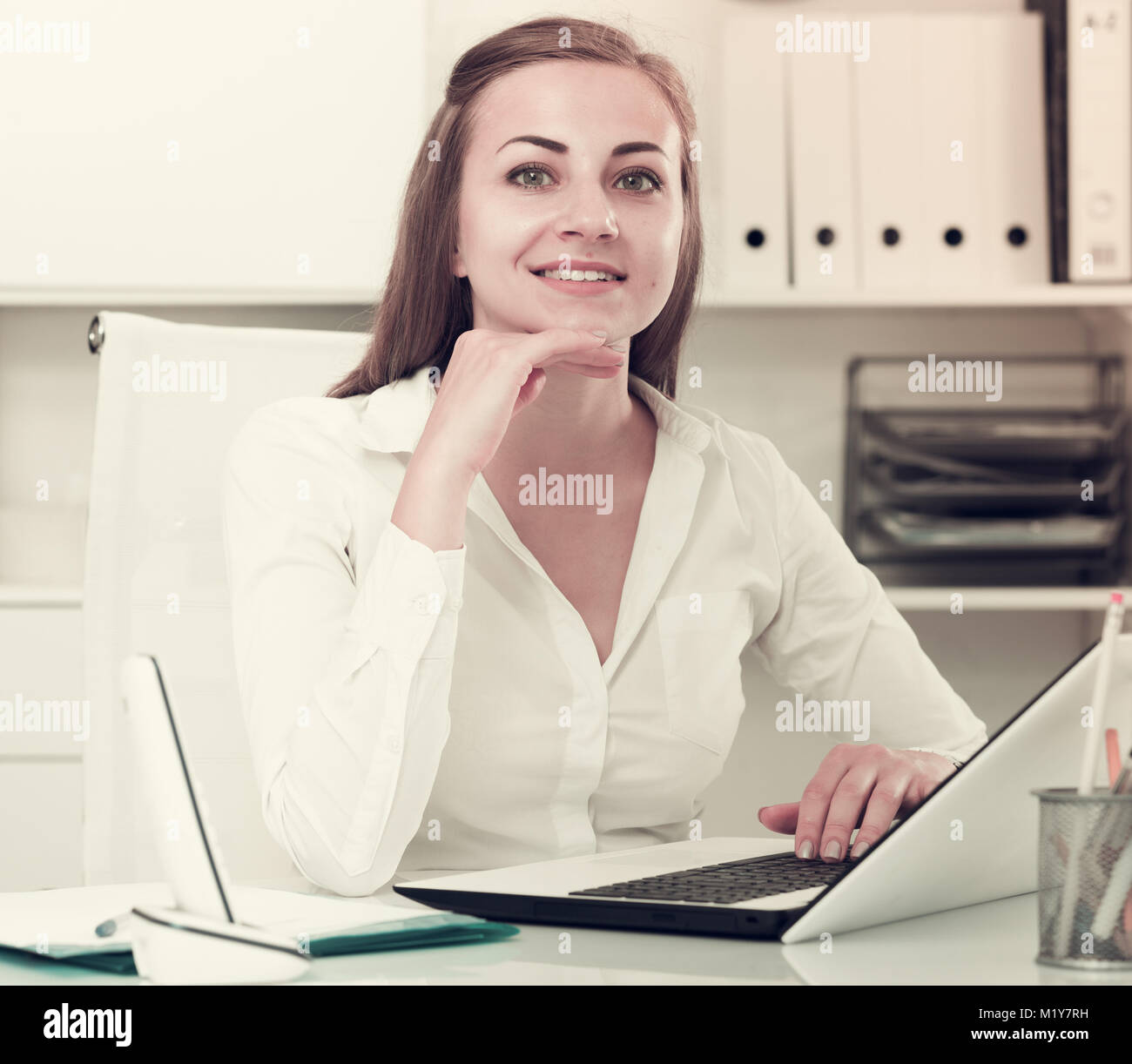 Female is posing while working behind laptop in the office Stock Photo ...