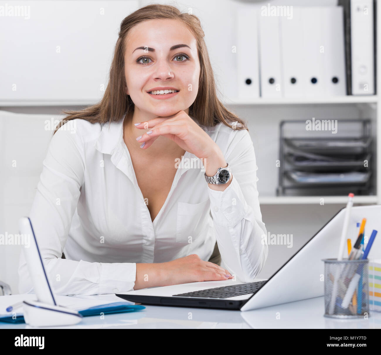 Female employee is posing while working behind laptop in the office ...