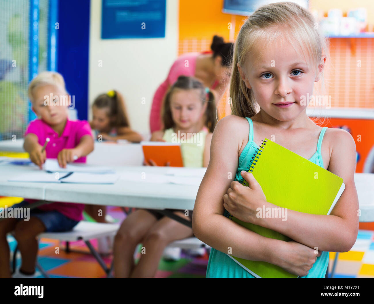 Portrait of cheerful smiling pretty pupil girl studying in school class ...