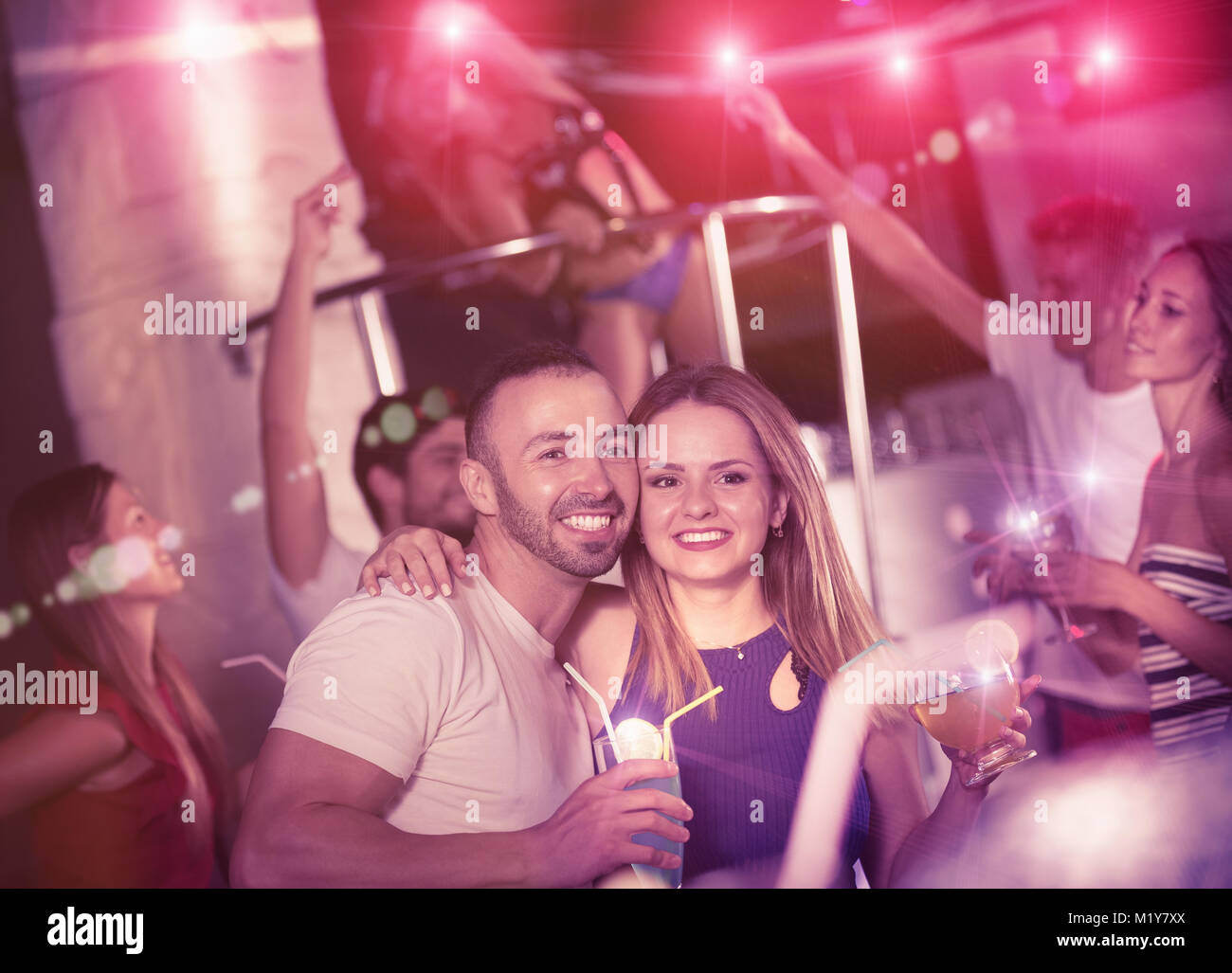 Positive man and woman dancing and hugging on party in the club with ...