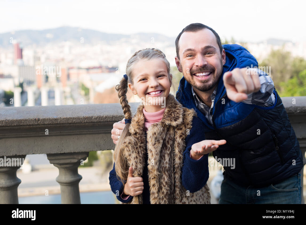 friendly father and daughter pointing at sight during sightseeing tour ...
