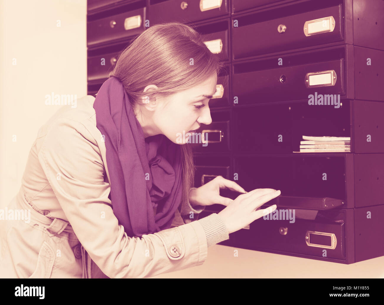 Sad girl in coat and scarf posing near empty mailbox Stock Photo - Alamy