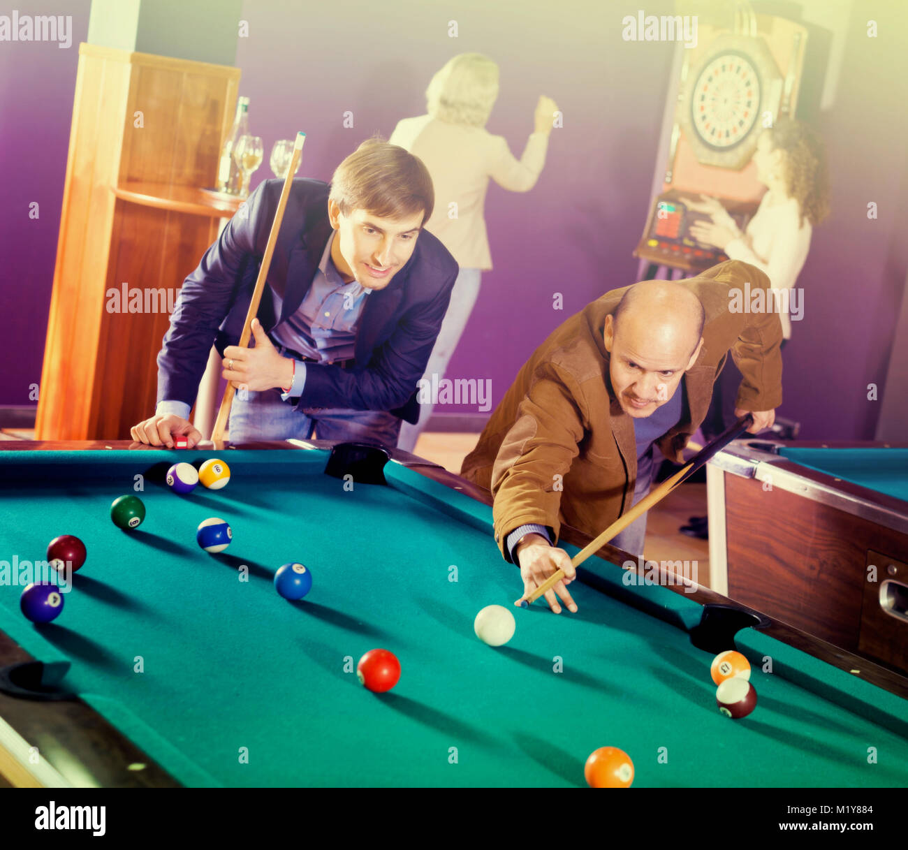 Group of happy charming positive friends playing billiards and smiling ...