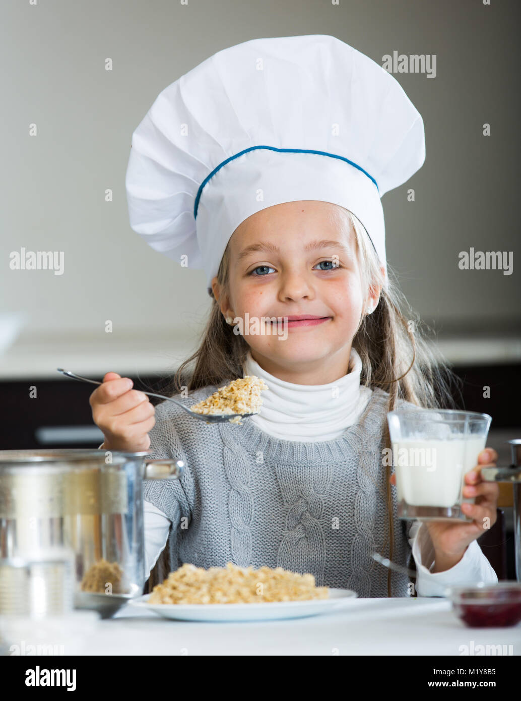 Little girl in cook hat with milk and oatmil kasha Stock Photo - Alamy