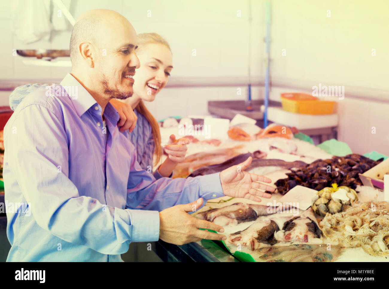 Ordinary russian customers choosing seafood in fish store and smiling ...