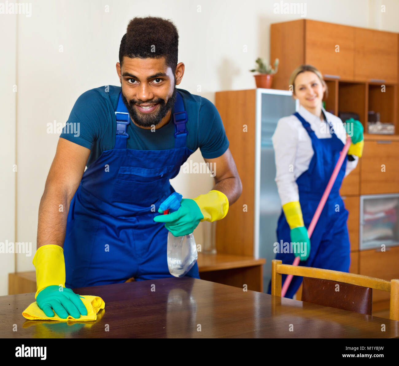 Positive cleaners cleaning and dusting in ordinary house Stock Photo ...