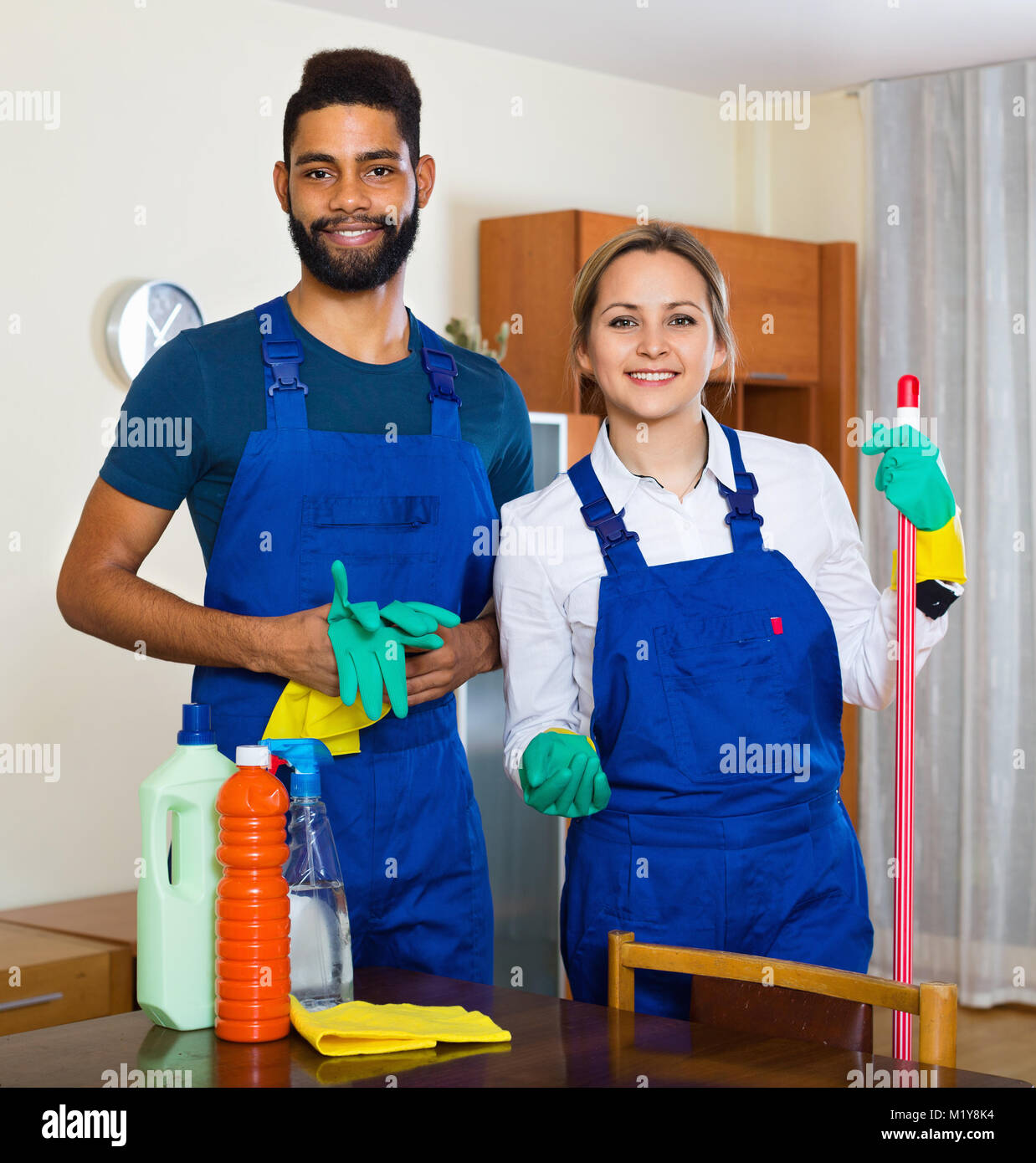 Positive smiling cleaners cleaning and dusting in ordinary house Stock ...