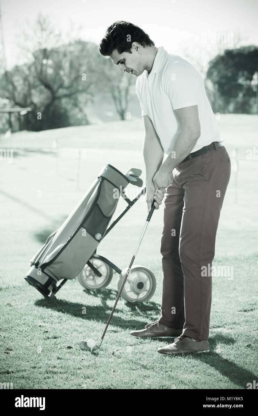 smiling russian man playing golf is going to hit ball at golf course ...