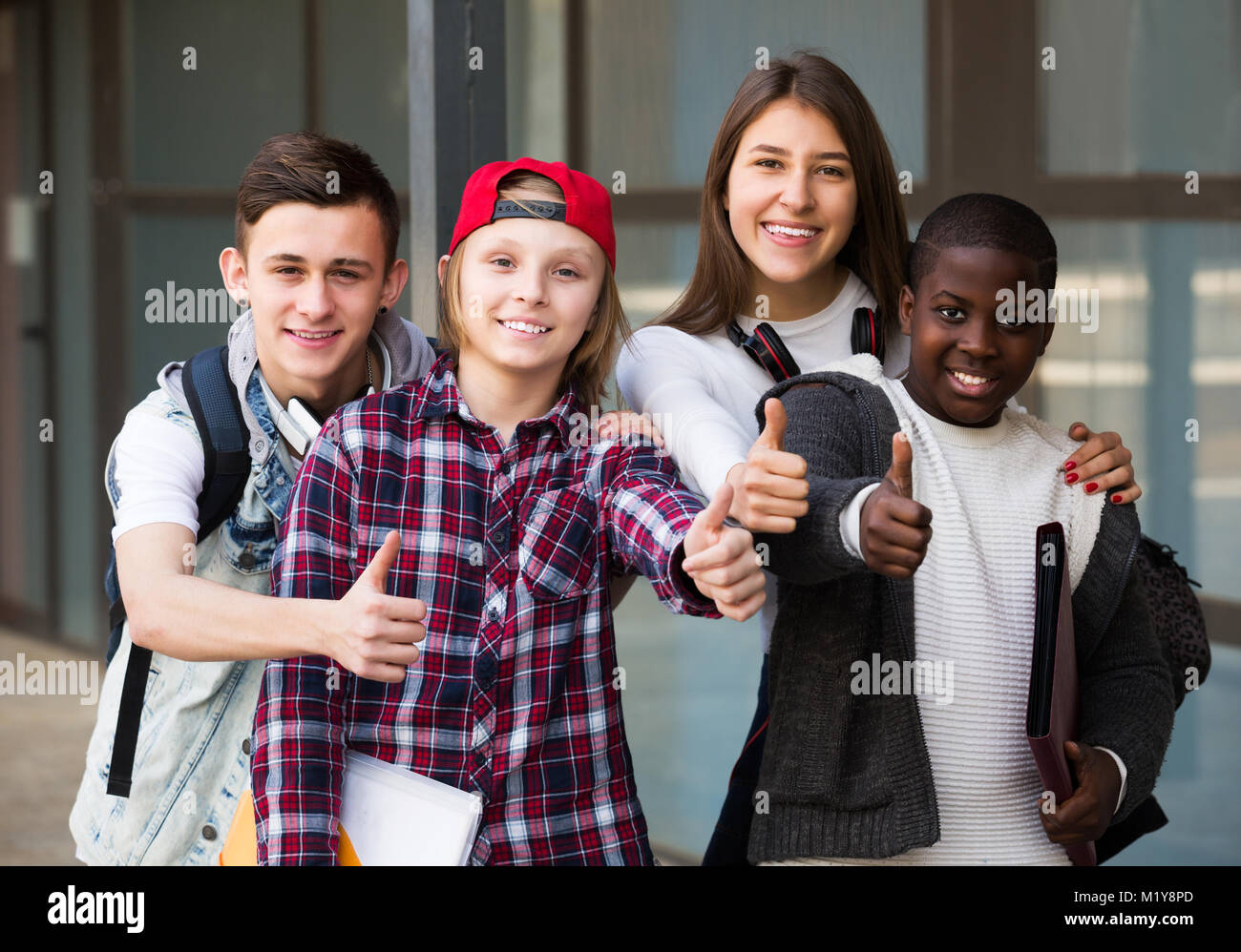 Portrait of four positive teenage students close to university Stock ...