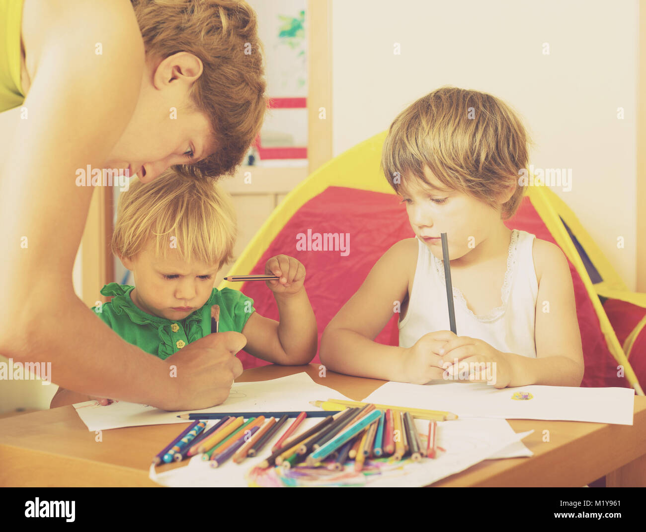 Serious mother and children drawing with pencils at home Stock Photo ...