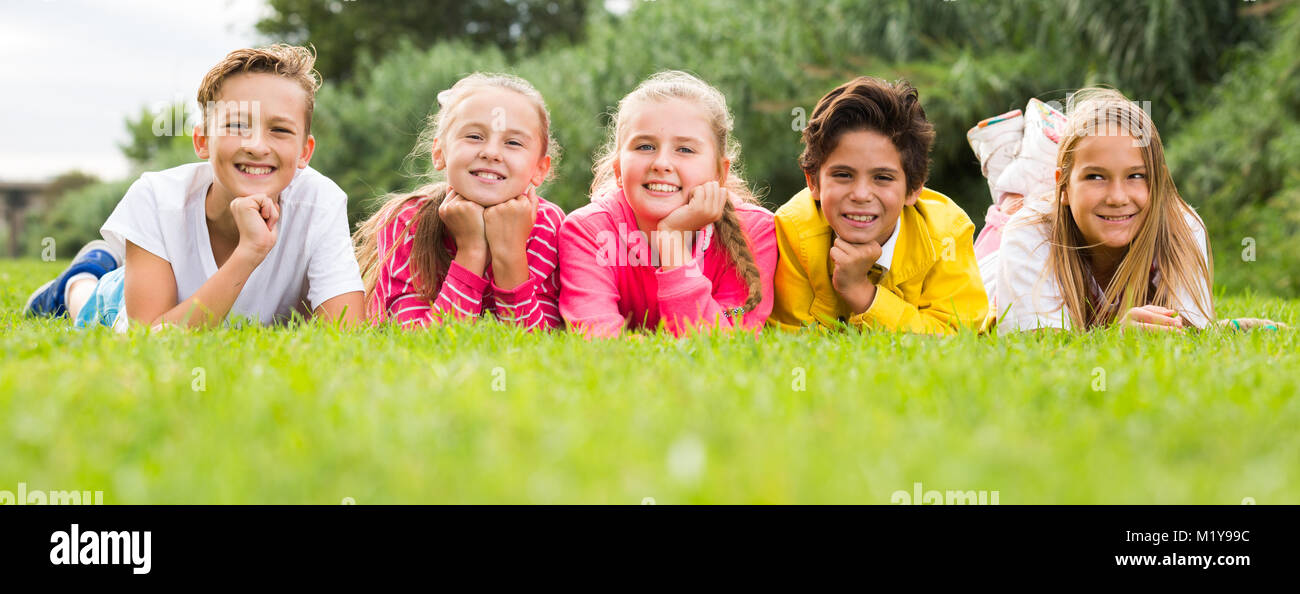 Portrait of five kids who are walking and posing lying in the park ...