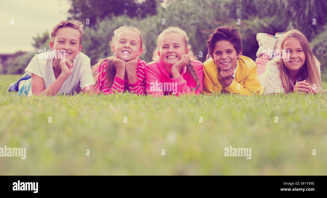 Portrait of five children who are walking and posing lying in the park ...