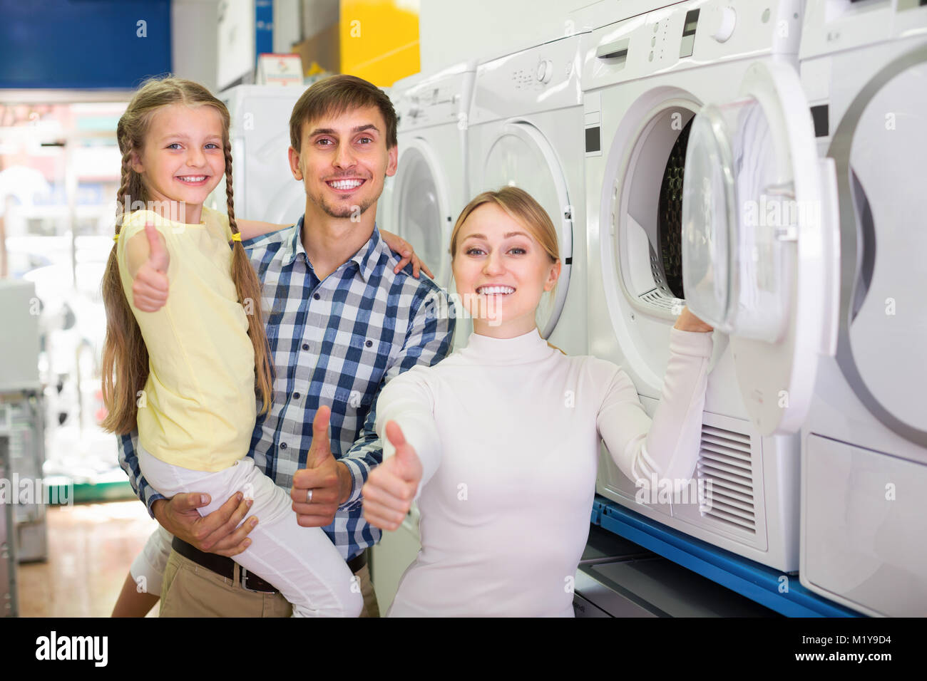 Happy family with girl selecting washing machine in hypermarket Stock ...