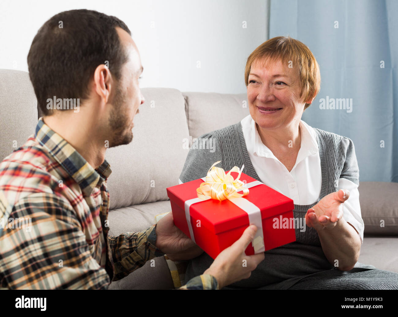 Son gives gift in red box to his elderly mother for birthday Stock ...