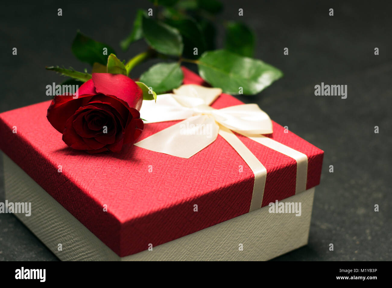 Red rose with gift box on dark background Stock Photo - Alamy