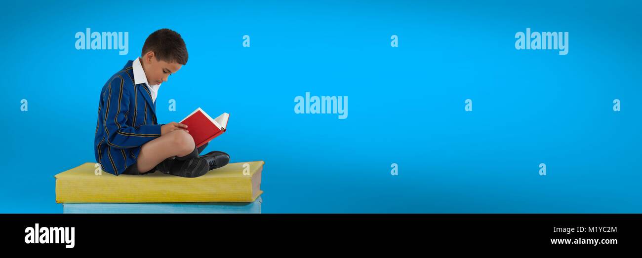 Boy reading and sitting on a pile of books with blue background Stock ...