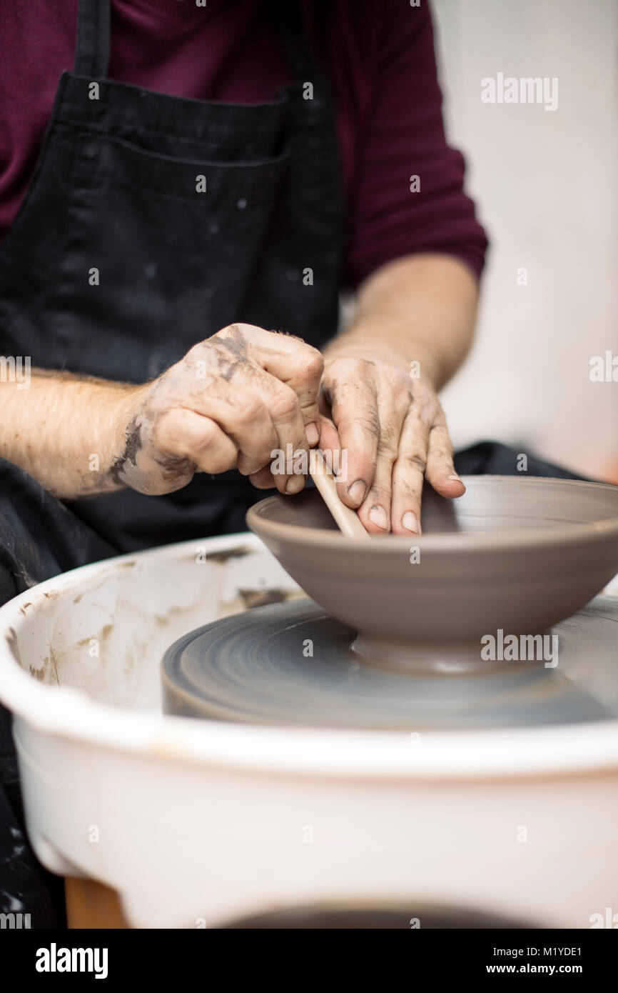 Close up detail view at an artist makes clay pottery on a spin wheel ...