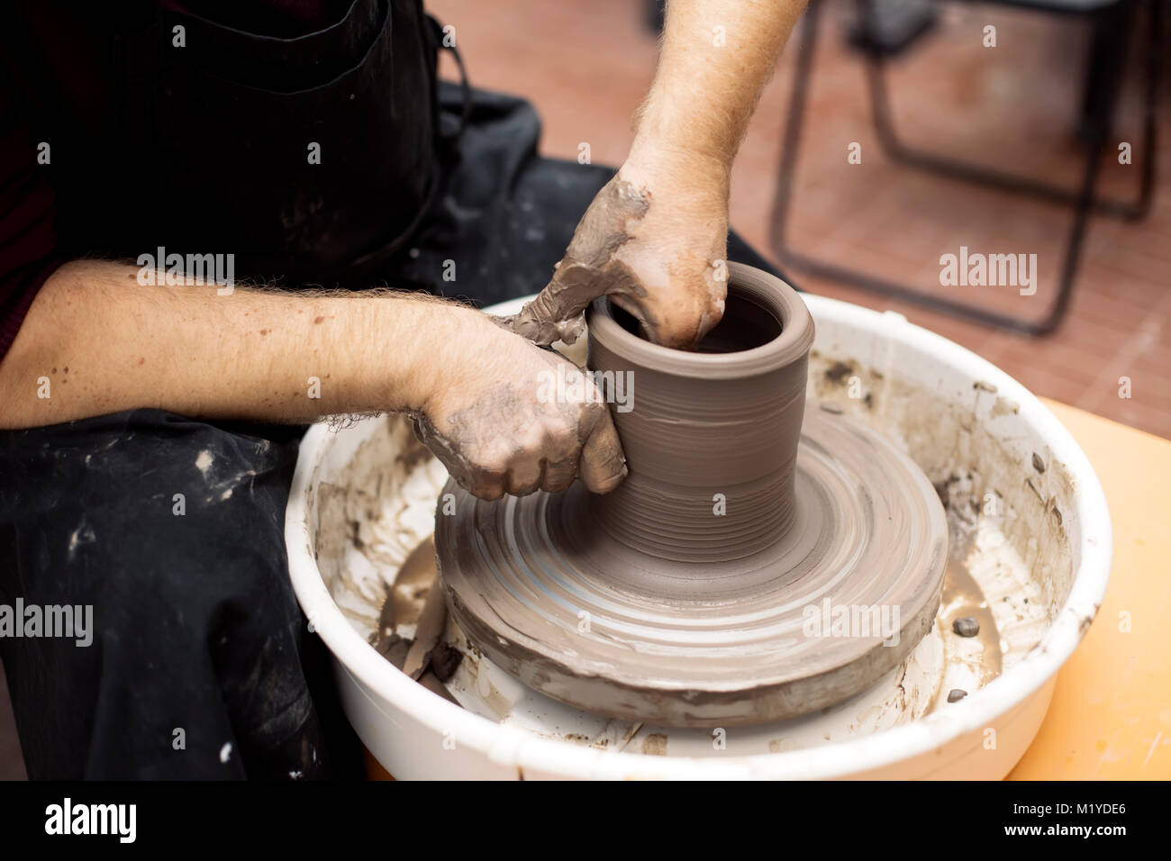 Close up detail view at an artist makes clay pottery on a spin wheel ...