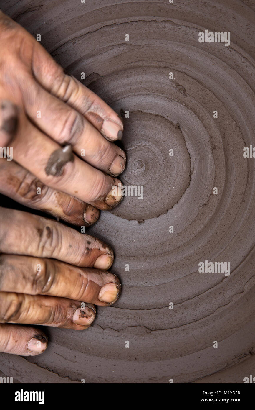 Close up detail view at an artist makes clay pottery on a spin wheel ...