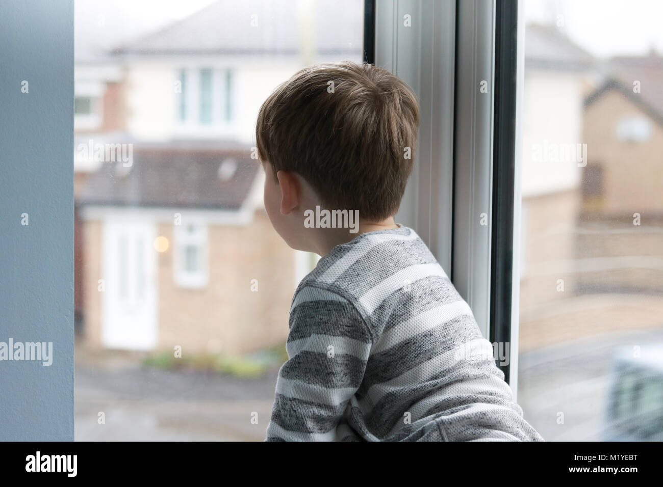 Boy looking out of bedroom window Stock Photo - Alamy