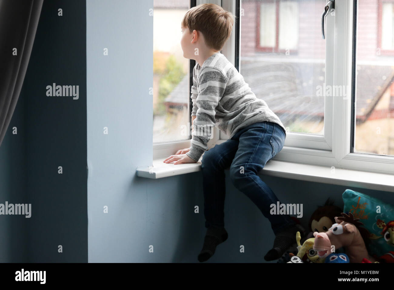 Boy looking out of bedroom window Stock Photo - Alamy