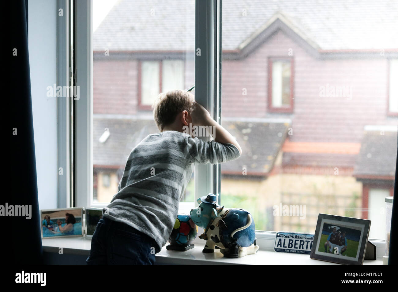 Boy looking out of bedroom window Stock Photo - Alamy