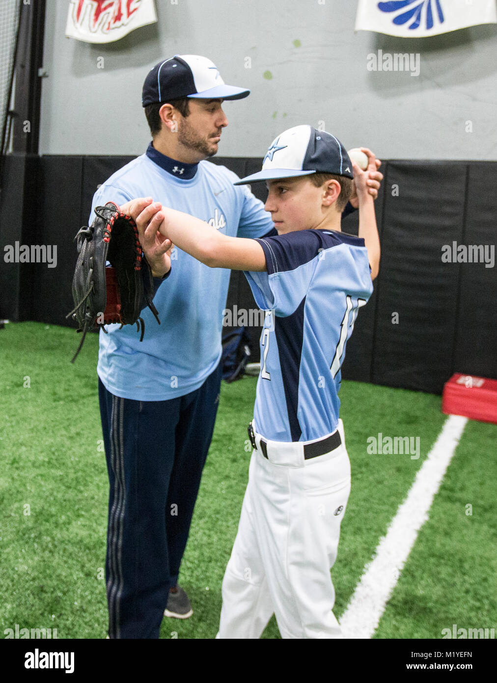 Baseball coach demonstrating proper throwing technique at an indoor ...