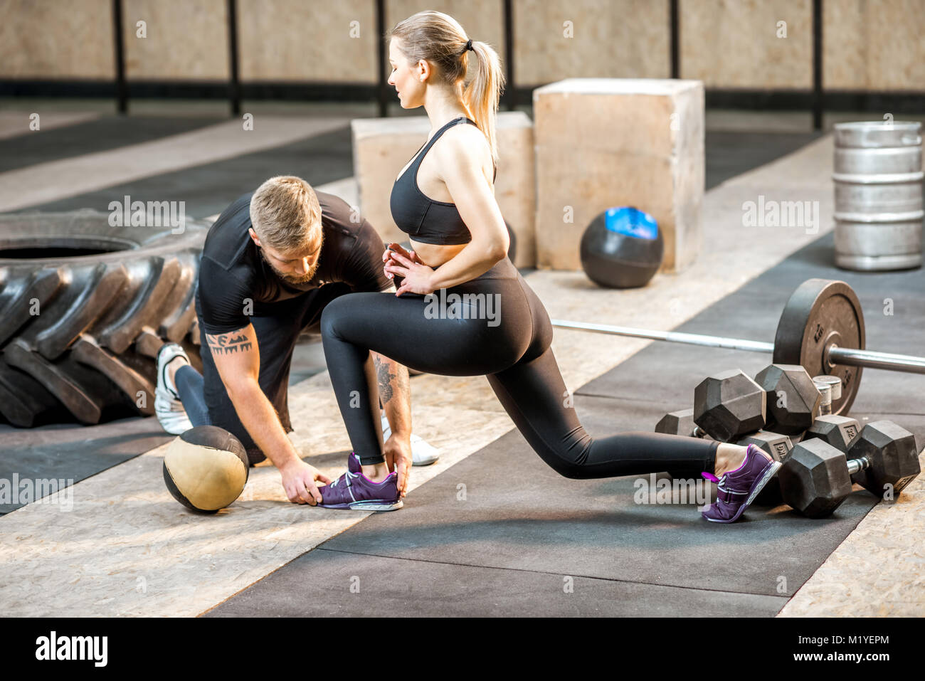 Woman squatting with trainer in the gym Stock Photo - Alamy
