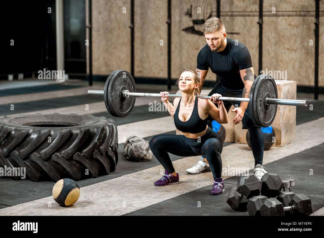 Woman lifting up a burbell with coach in the gym Stock Photo - Alamy