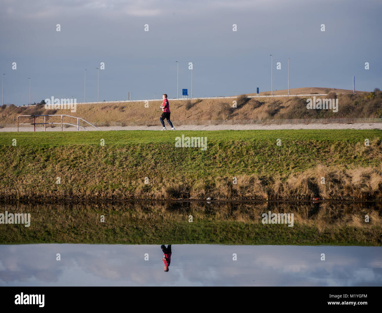 A jogger runs alongside a coastal path in a public park Stock Photo - Alamy