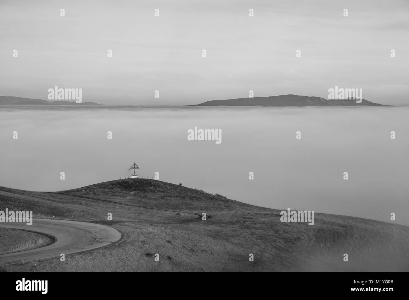Black and white picture of a wooden cross atop a small hill overlooking ...