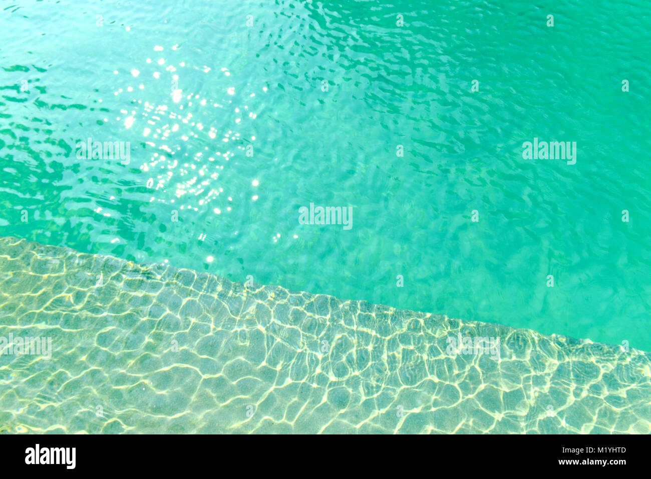 Swimming pool blue water with a wave and sunlight reflection effect ...