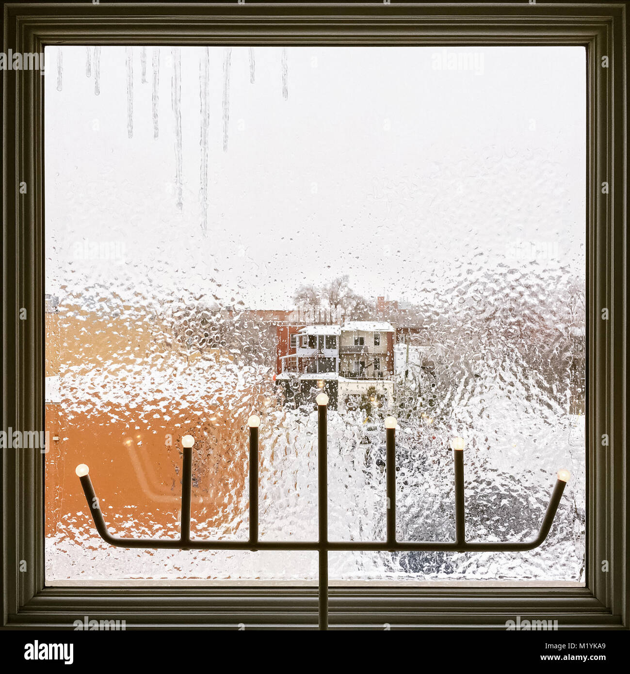 Icicles on a frosted window decorated with LED lights. Weather after ...