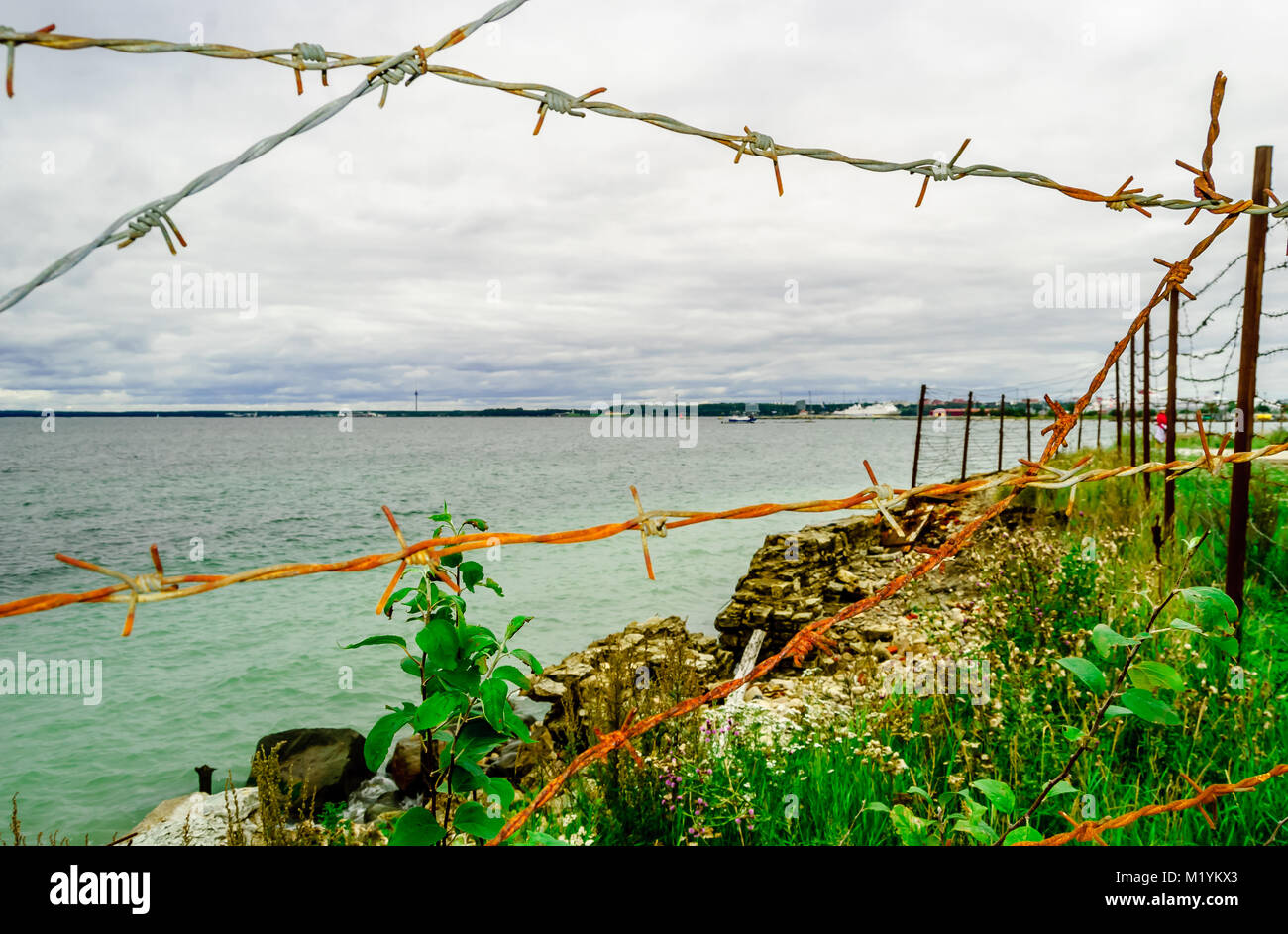 View on Fence of Barb wire protect coastline of sea Stock Photo - Alamy