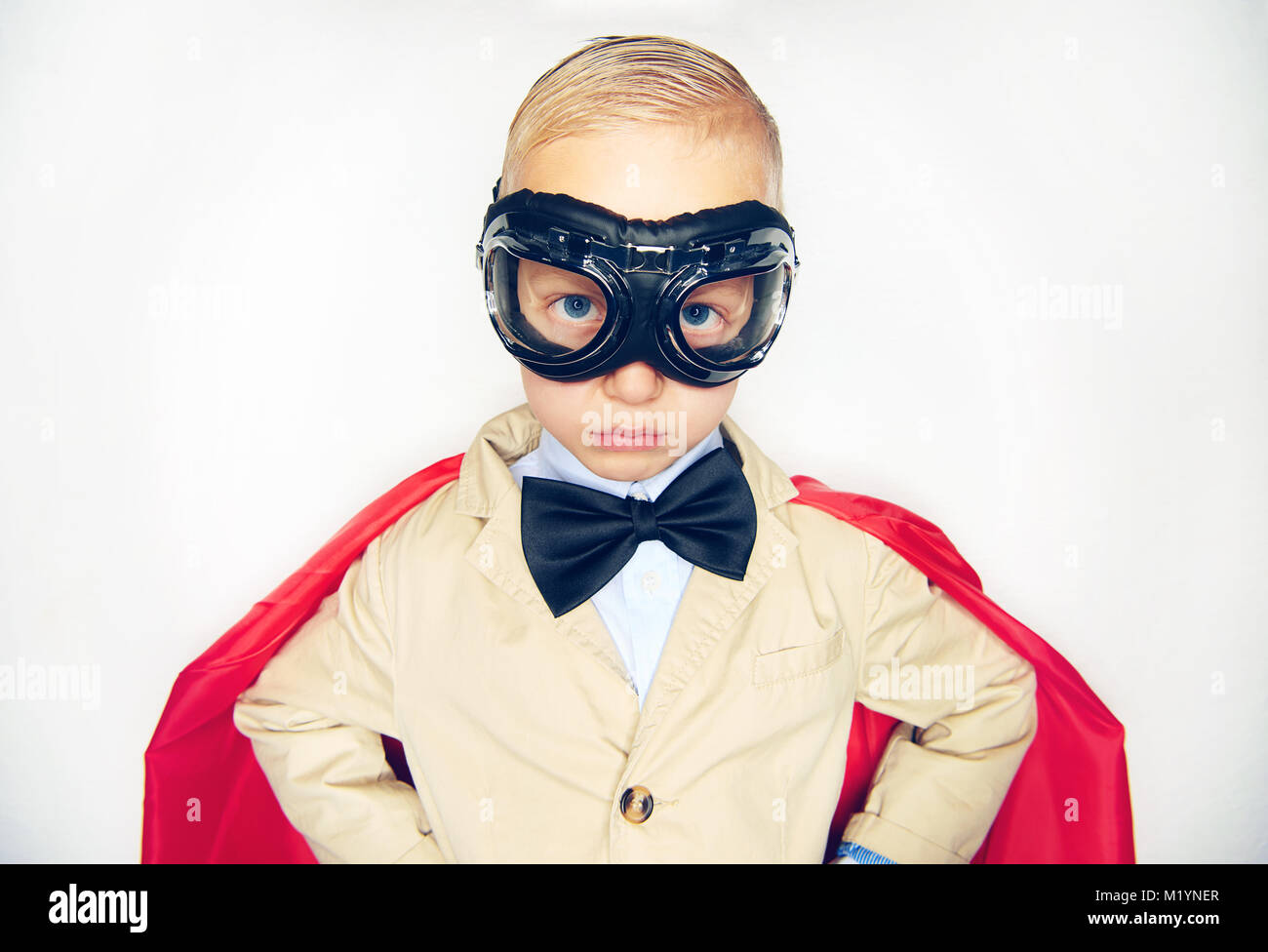 Little boy in aviator glasses and red cloak posing with hands on hips ...