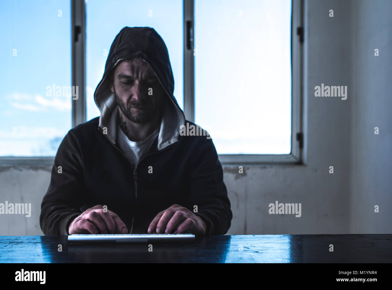 Hacker with laptop. Window in background Stock Photo - Alamy