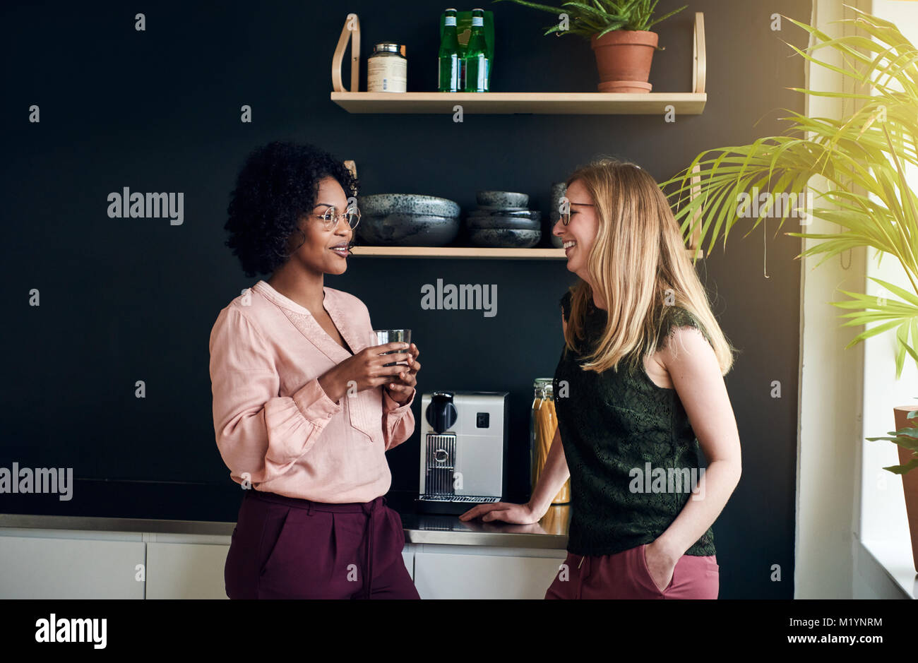 Two smiling young female work colleagues having a conversation together ...